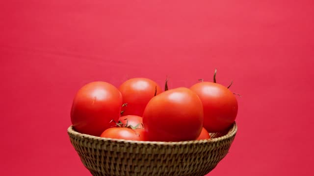Red background - Hand putting down spinning tomato on basket filmed by ...