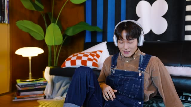 Gen Z - Man sitting in front of couch wearing headphones and dancing ...