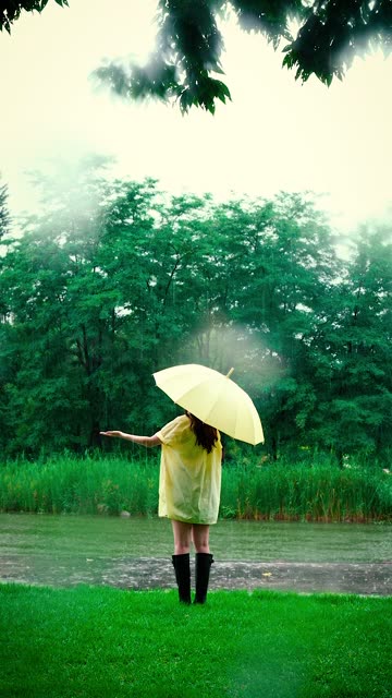 Rainy Day - woman with yellow umbrella reaching out her hand to touch ...