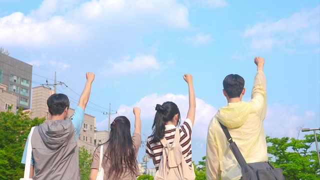 Back of college students turning back and shaking fists with arms up ...